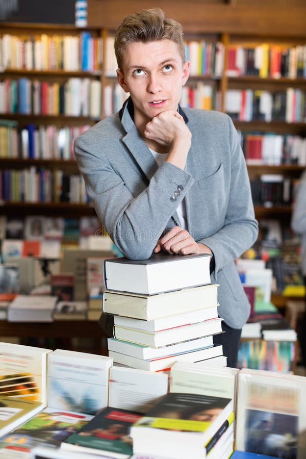 Pensive Young Man Posing on Stack of Books in Bookstore Stock Image ...