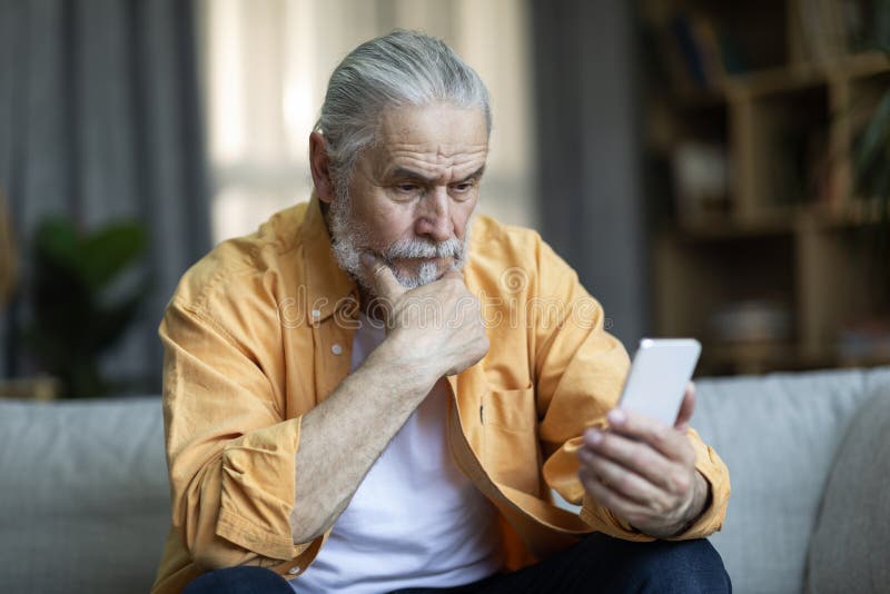 Pensive Elderly Man Sitting on Couch, Using Smartphone Stock Photo ...