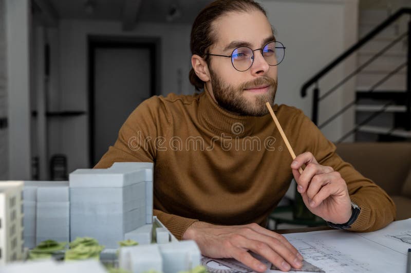 Pensive Engineer in Glasses Sitting at the Table and Creating Blueprint ...