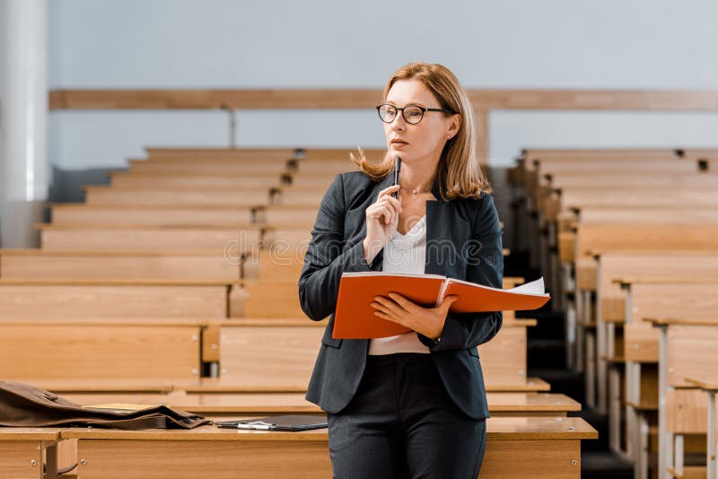 Pensive Female University Professor Holding Journal and Looking Away ...
