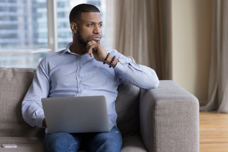 Pensive Guy Deep in Thoughts Sitting on Sofa with Laptop Stock Photo ...