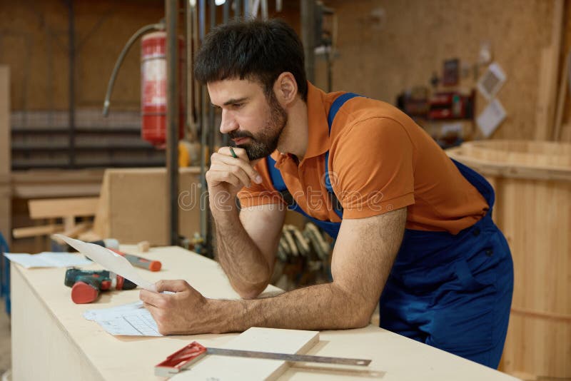 Pensive Man Carpenter Reading Blueprints and Thinking during ...