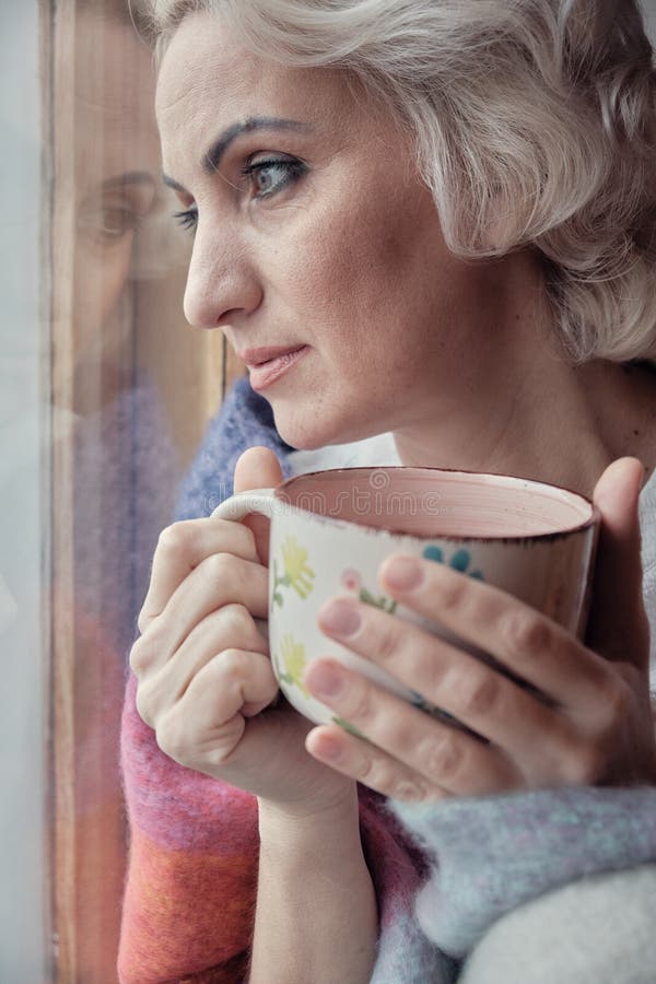 Pensive Mature Woman Drinking Tea and Looking Out Window, Lockdown and ...