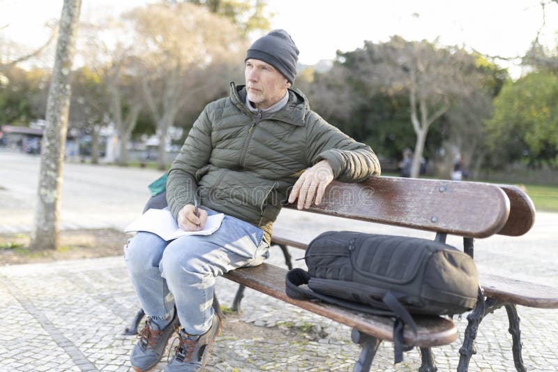 Pensive Senior Man Writing in Notebook while Sitting on Park Bench ...