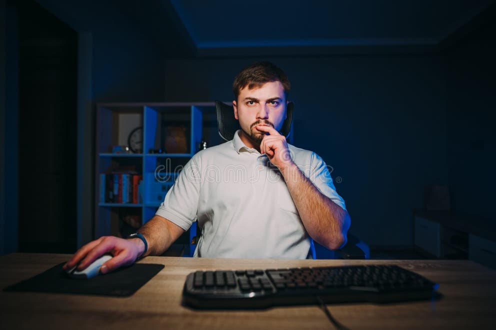 Pensive Serious Man Working at Night at the Computer, Looking at the ...
