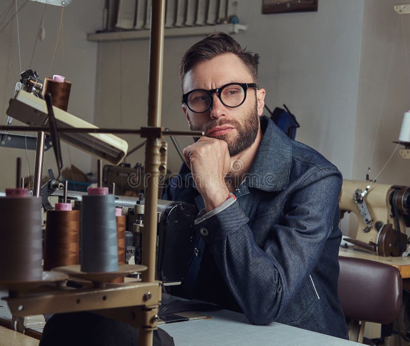 Pensive Tailor Sitting at a Table with Hand on Chin in a Sewing ...
