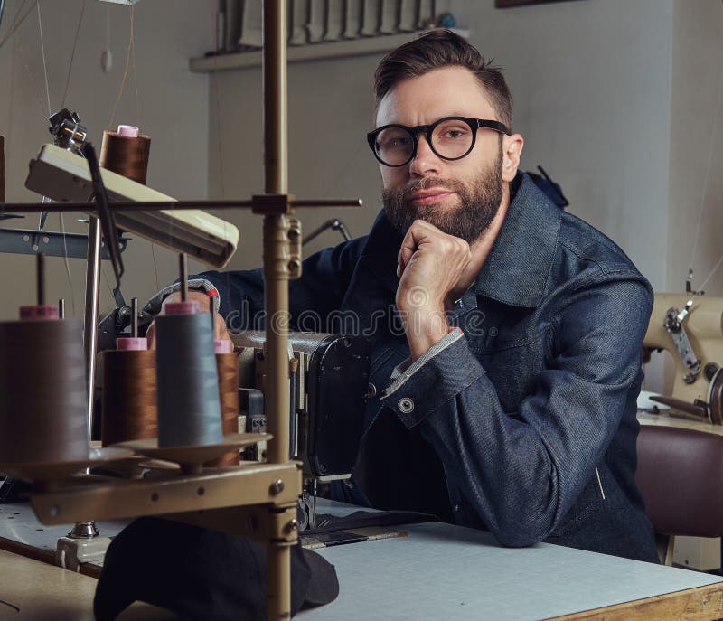 Pensive Tailor Sitting at a Table with Hand on Chin in a Sewing ...