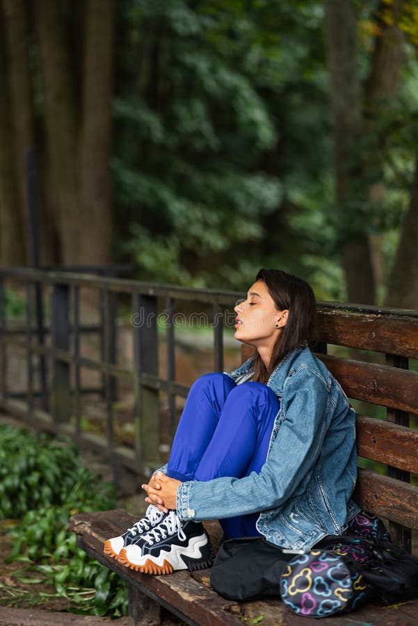 Pensive Woman Sitting on a Bench in a Park Looking Away Stock Image ...