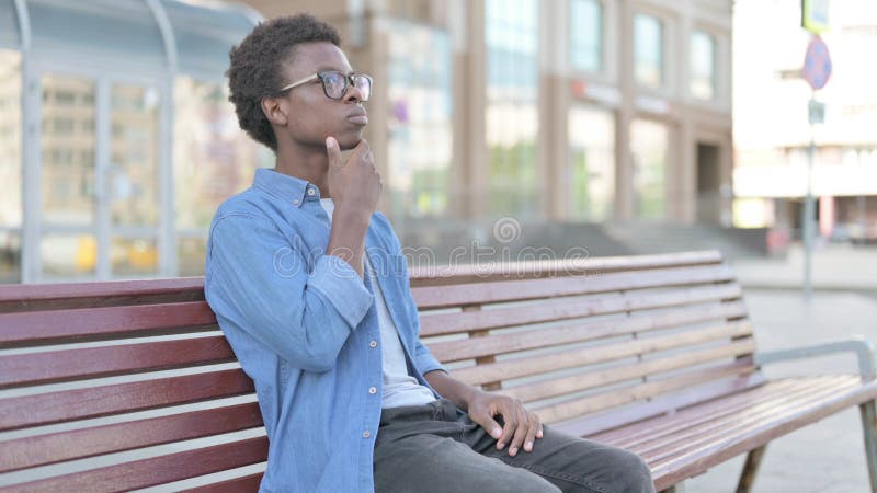 Pensive Young African Man Thinking while Sitting Outdoor on Bench Stock ...