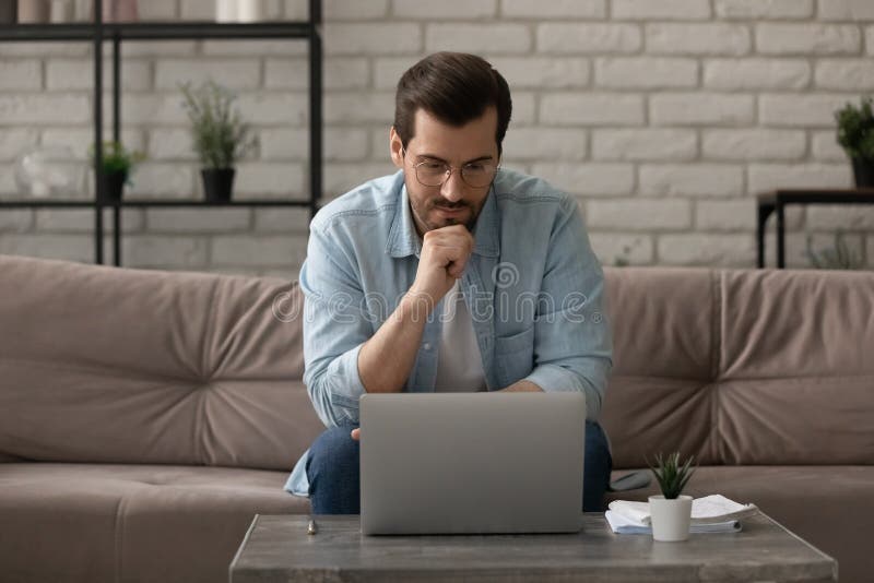 Pensive Young Male Working at Home Focused on Computer Screen Stock ...