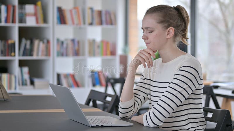 Pensive Young Woman Reading on Laptop in Library Stock Image - Image of ...