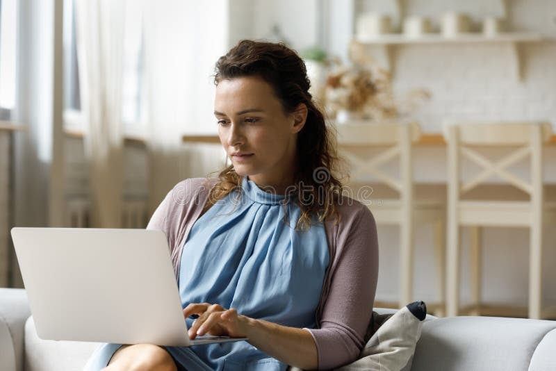 Pensive Young Woman Using Computer Sitting on Couch. Stock Image ...