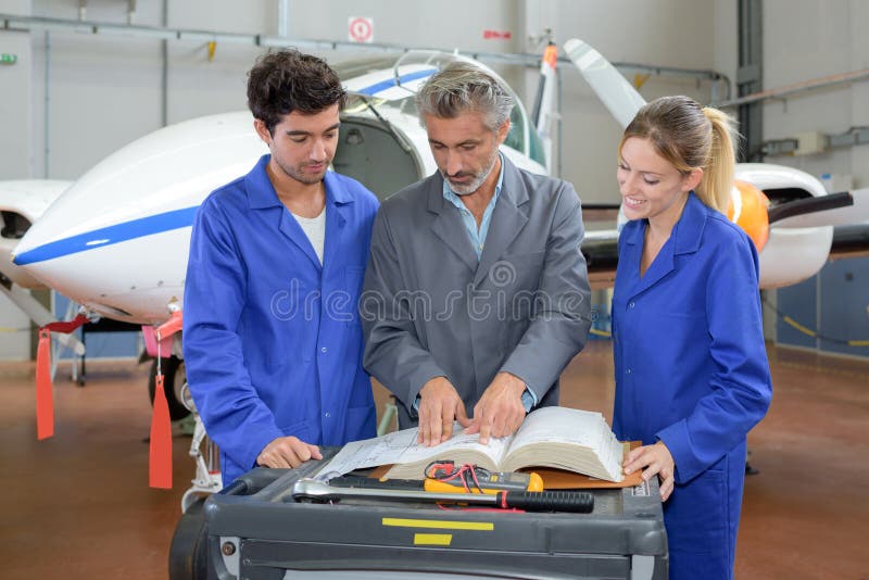 People in Aircraft Hangar Looking at Manual Stock Image - Image of ...