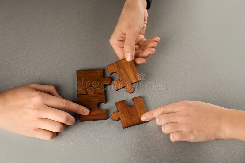 People Assembling Wooden Puzzle on Grey Background Stock Photo - Image ...