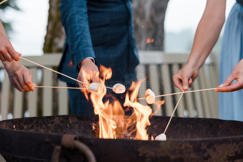 People Cooking Marshmallows on Sticks Over a Flaming Fire Pit Stock ...