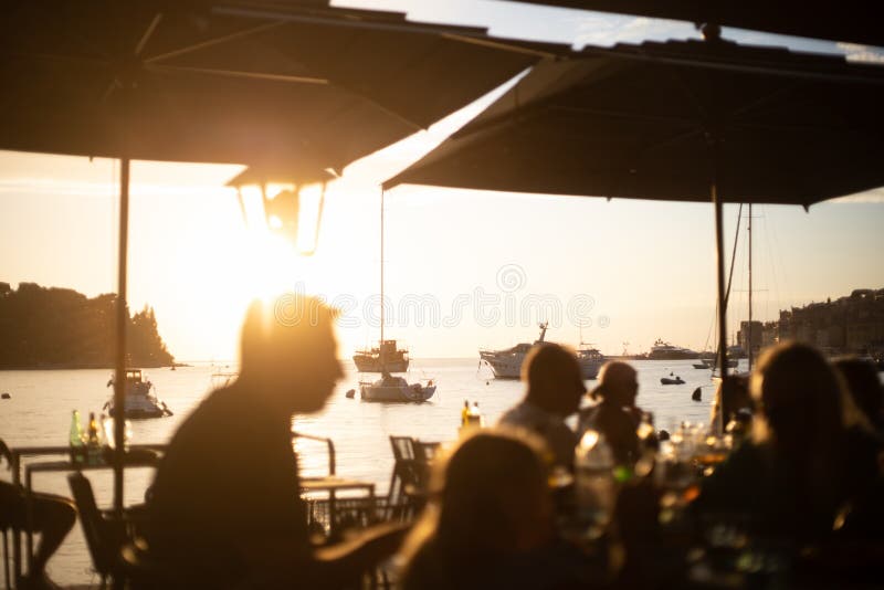 People Dining at Seaside Restaurant with Romantic Sunset Stock Image ...