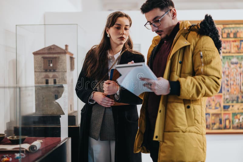 Two Individuals Exploring a Historical Exhibit and Taking Notes in a ...