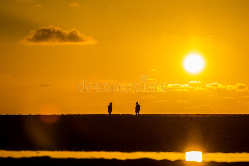 People Facing Each Other on Beach in Golden Light at Sunset Stock Photo ...