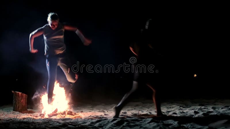 People Jumping Over Bonfire on the Beach at Night Stock Video - Video ...