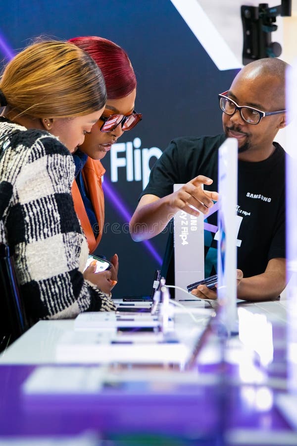 People Studying the Features of Smartphones Displayed on a Store Table ...