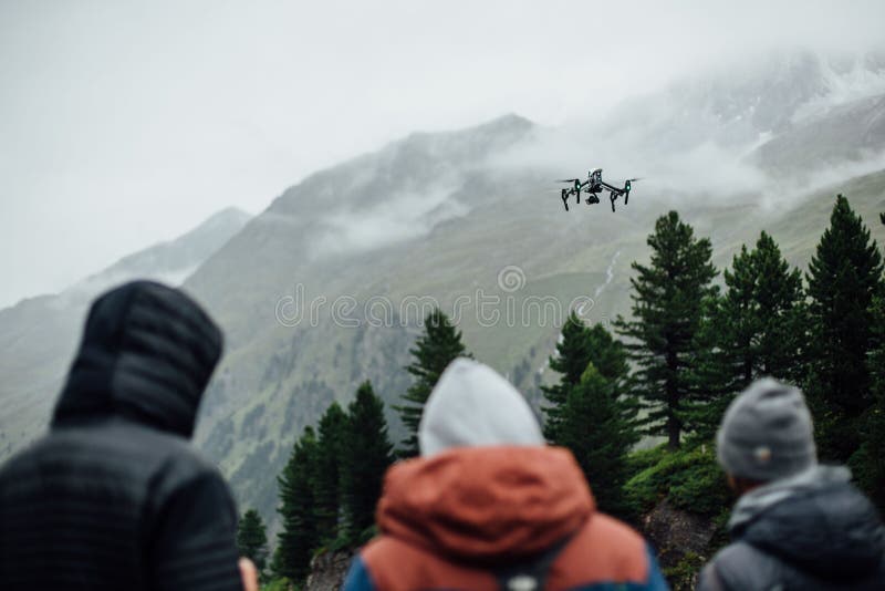 People Watching the Drone Flying Over the Trees and Mountains Covered ...