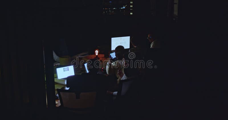People Working Late in a Dark Office, Using Laptops and Desktop ...
