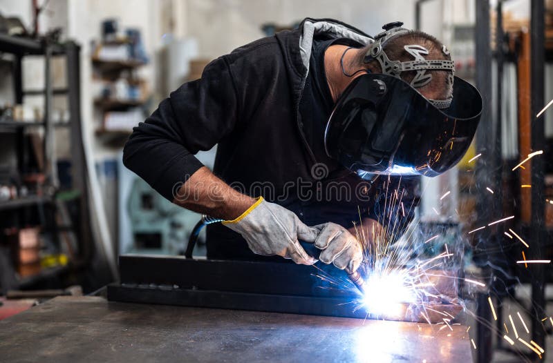 Performing a Weld: the Man in the Welding Mask is Positioned with the ...