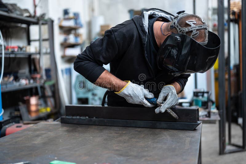 Performing a Weld: the Man in the Welding Mask is Positioned with the ...