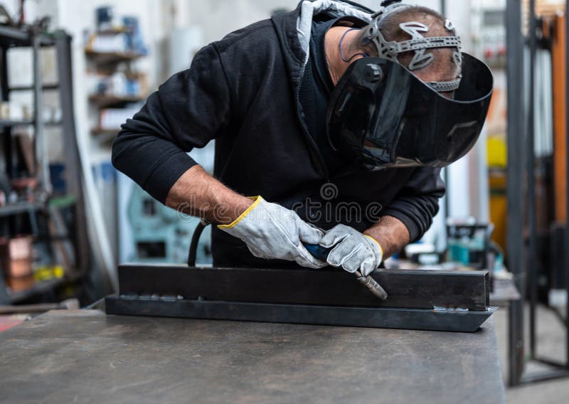 Performing a Weld: the Man in the Welding Mask is Positioned with the ...