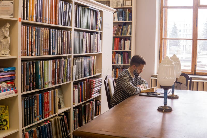 Young Man Reading a Book in a Library. Student Studying in a Library ...