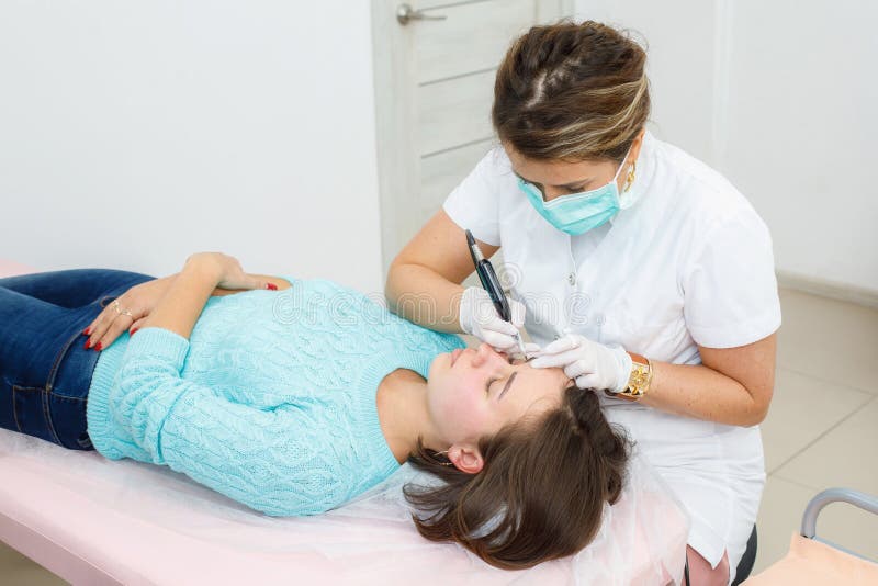 Permanent Makeup, Tattooing of Eyebrows. Cosmetologist Applying Make Up ...