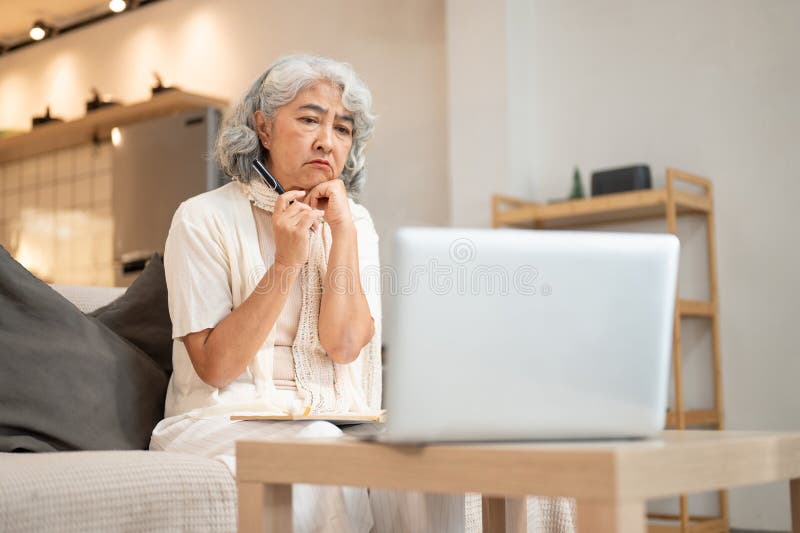 A Perplexed Asian Senior Woman Faces a Problem while Using Her Laptop ...