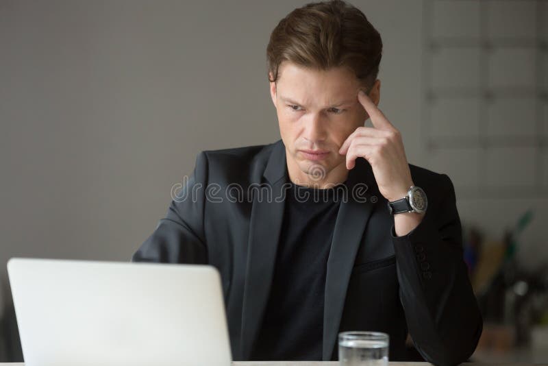 Perplexed Young Businessman Looking at Laptop Screen at Workplac Stock ...