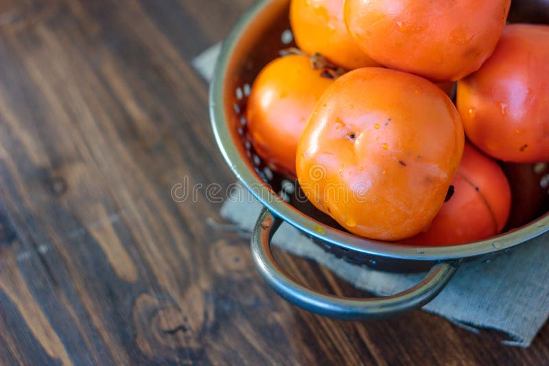 Persimmons in Metal Collander on Wooden Table. Stock Photo - Image of ...