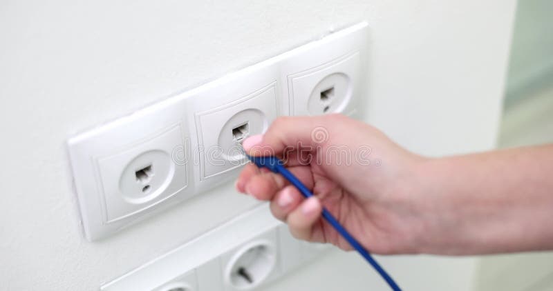 A Person is Carefully Plugging in a Blue Ethernet Cable into a Wall ...