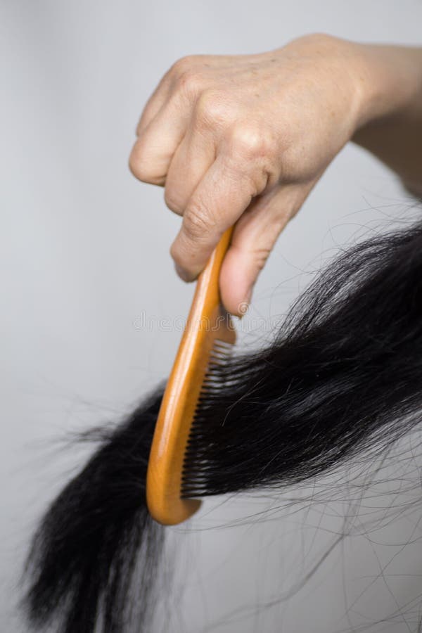 Person Combing Long Black Hair with a Grey Background Stock Photo ...