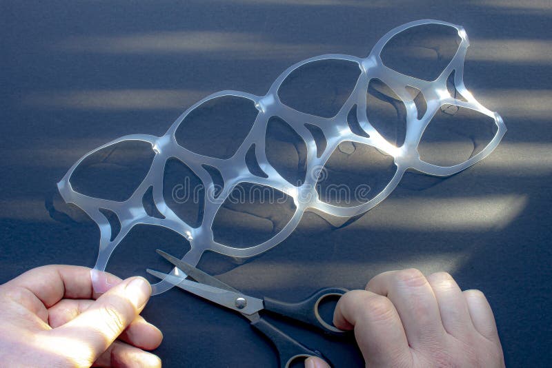 A Person Cutting a Eight Pack Rings or Eight Pack Yokes with Scissors ...