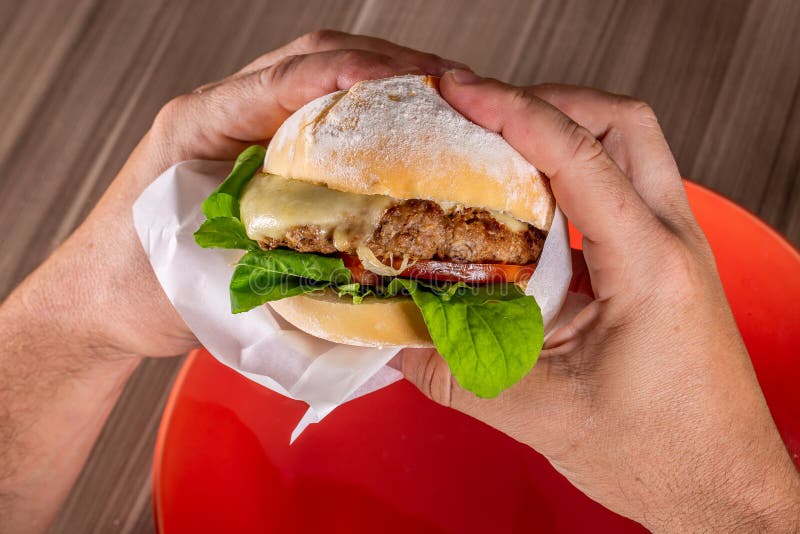 Person Eating Cheeseburger with Arugula and Tomato Stock Image - Image ...