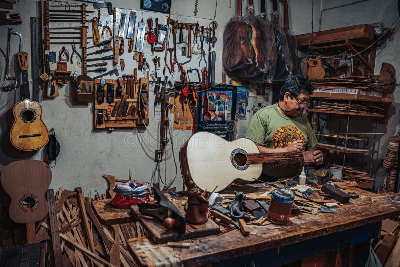 A Person Working on a Guitar in a Garage Surrounded by Various Guitars ...