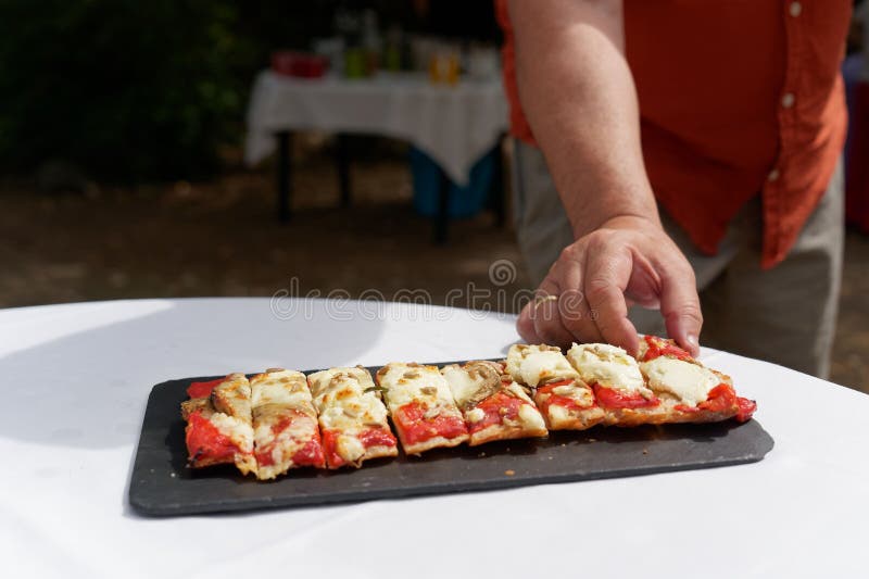 A Person Grabbing Up Some Pizza on a Rectangular Tray on a Table Stock ...