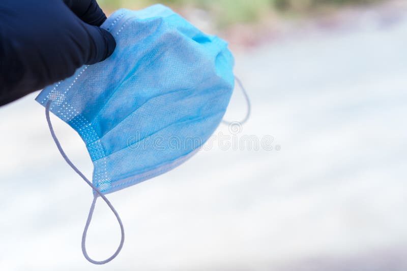 Person Holding a Blue Protective Face Mask with a Blurry Background ...