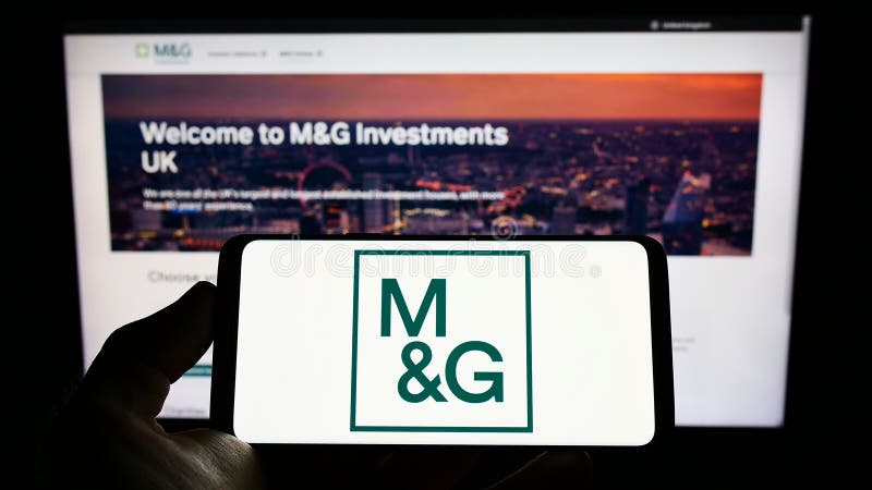 Person Holding Smartphone with Logo of British Investment Company M and ... Person Holding Smartphone with Logo of British Investment Company M and ...