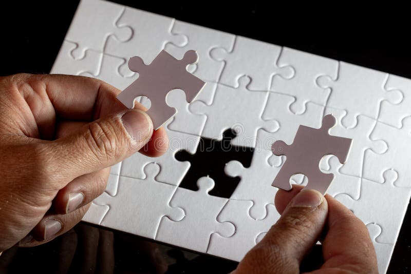 A Person is Holding Two Pieces of a Jigsaw Puzzle, One of Which is ...
