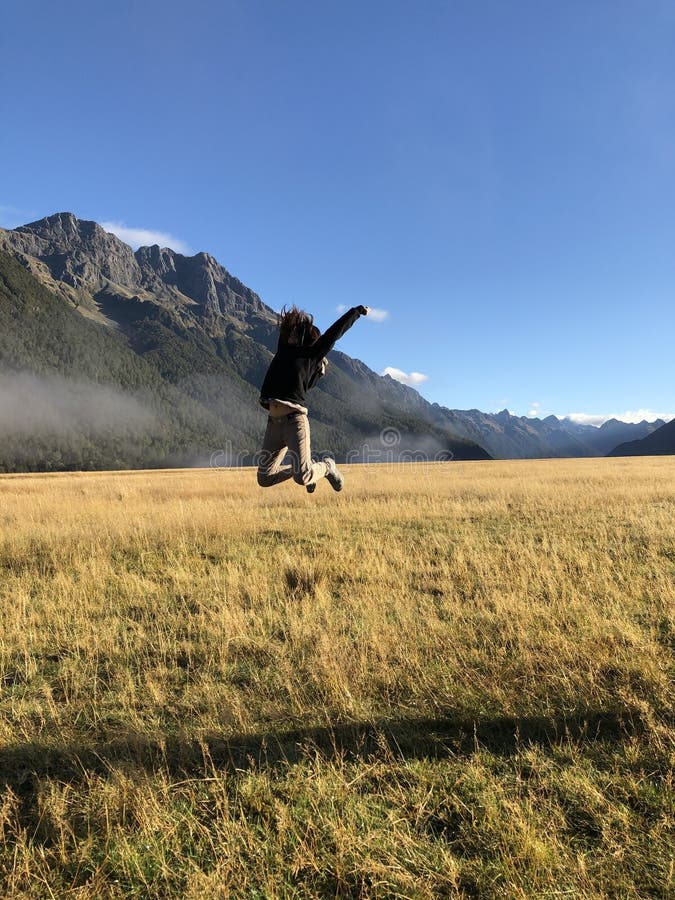 Person Jumping in Meadow with Mountain Backdrop Stock Image - Image of ...