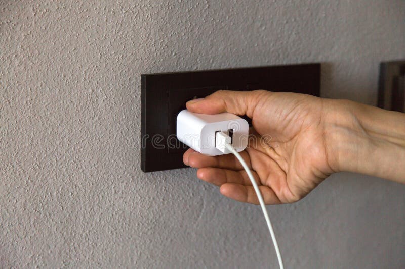 A Person is Plugging a White USB Charger into a Black Wall Socket ...