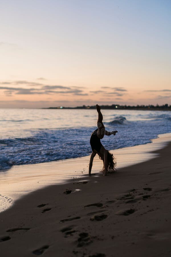 Person Practicing Yoga Poses at Sunset on a Sandy Beach. Stock Image ...