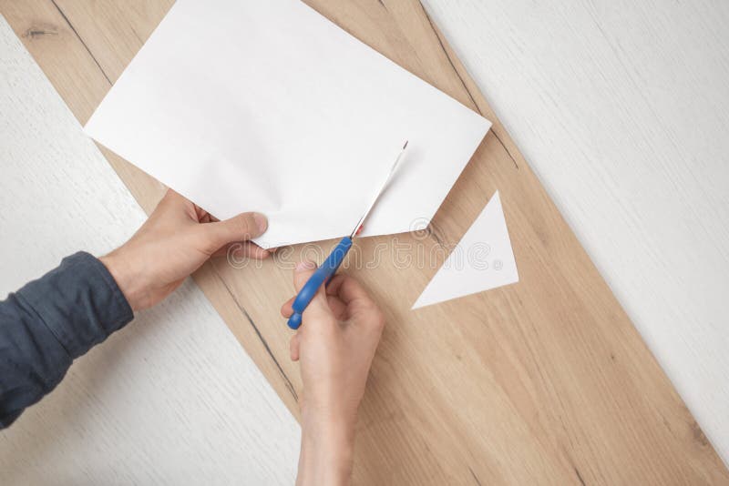 A Person S Hands Holding Piece of Paper Sheet and Cut it with Scissors ...