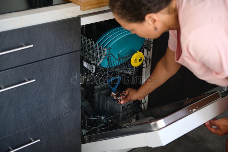 Person Loading a Dishwasher with Dishes and Cutlery in a Modern Kitchen ...
