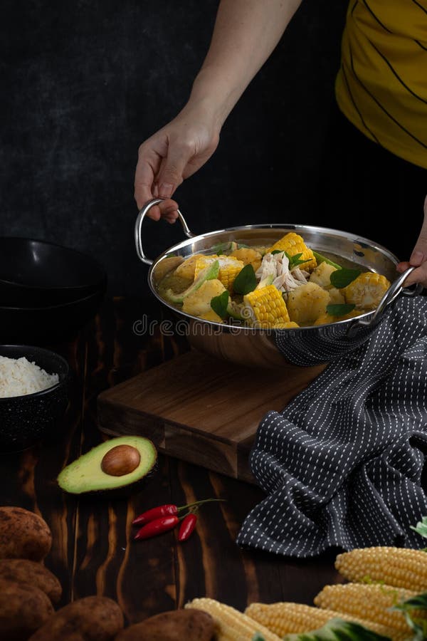 A Person Serving a Pot of Chicken Soup with Potato and Corn Stock Photo ...