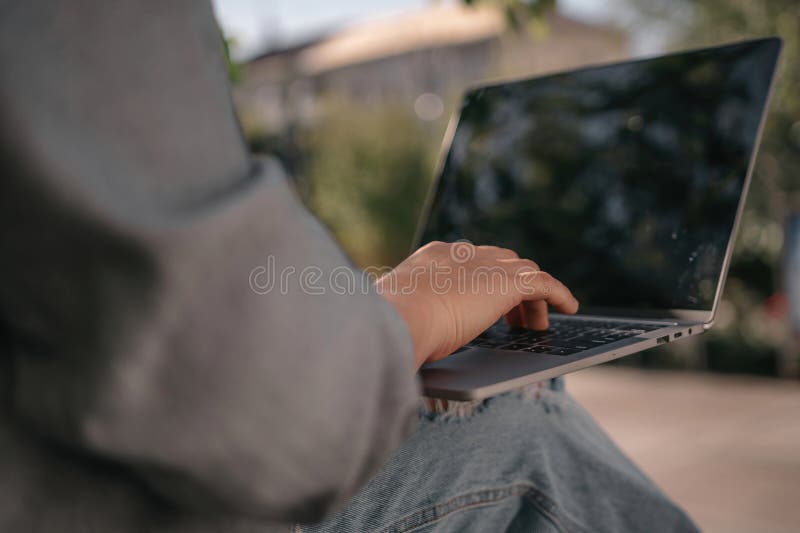 A Person is Sitting on a Bench with a Laptop Open in Front of Them ...